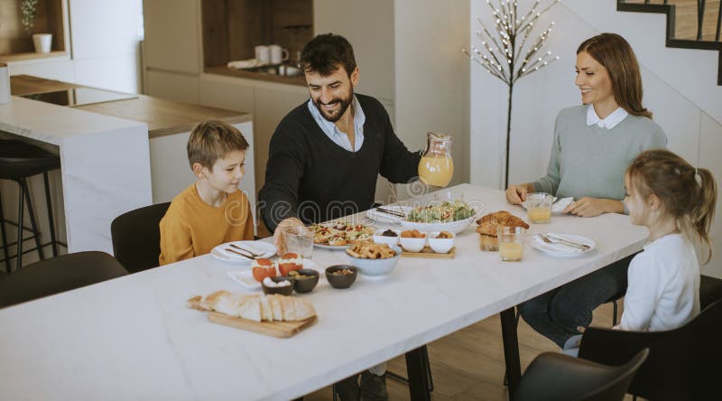 Young Happy Family Talking while Having Breakfast at Dining Table Stock ...
