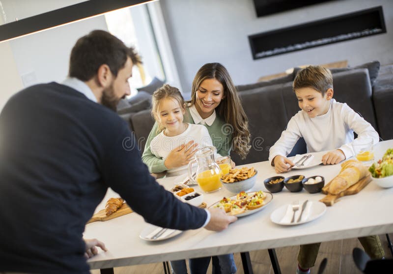 Young Happy Family Talking while Having Breakfast at Dining Table Stock ...
