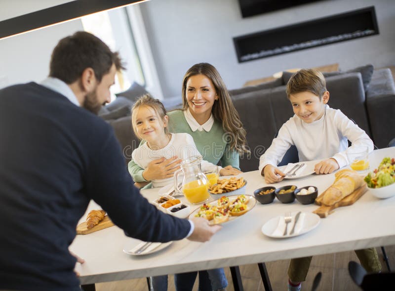 Young Happy Family Talking while Having Breakfast at Dining Table Stock ...