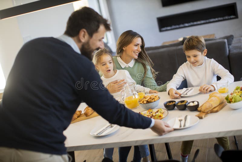 Young Happy Family Talking while Having Breakfast at Dining Table Stock ...