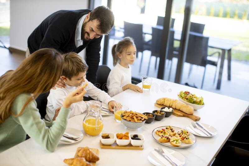 Young Happy Family Talking while Having Breakfast at Dining Table Stock ...