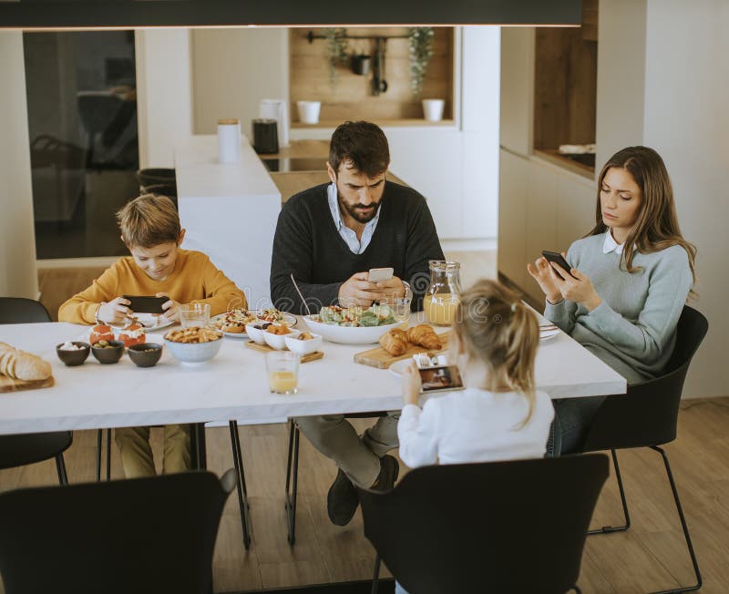 Young Happy Family Talking while Having Lunch at Dining Table Stock ...