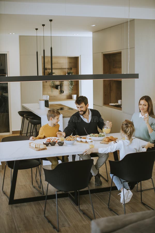Young Happy Family Talking while Having Lunch at Dining Table Stock ...