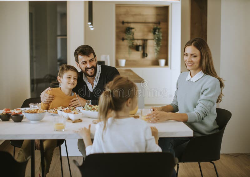 Young Happy Family Talking while Having Lunch at Dining Table Stock ...