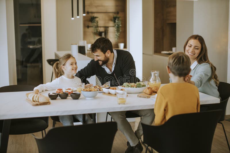 Young Happy Family Talking while Having Lunch at Dining Table Stock ...