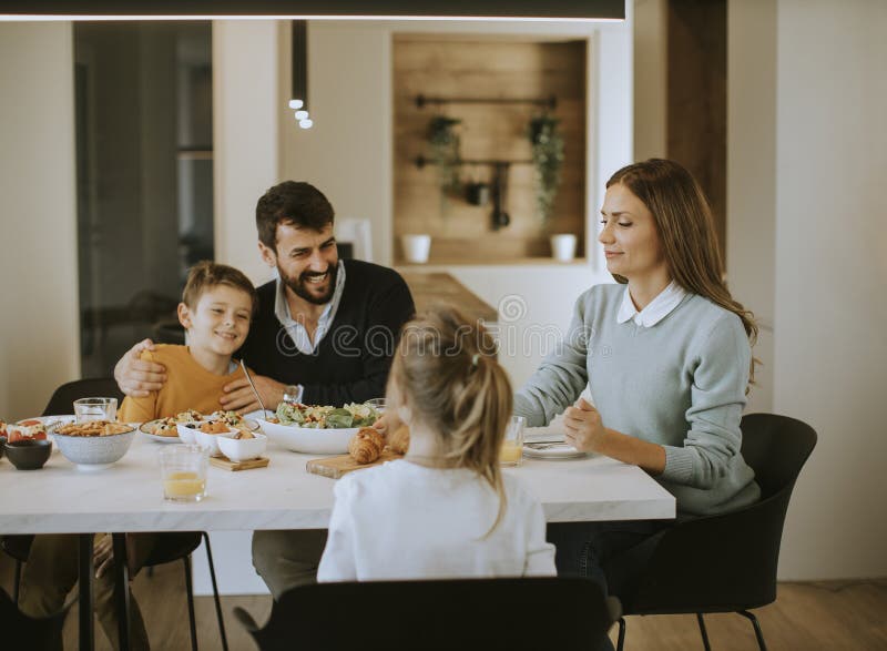 Young Happy Family Talking while Having Lunch at Dining Table Stock ...