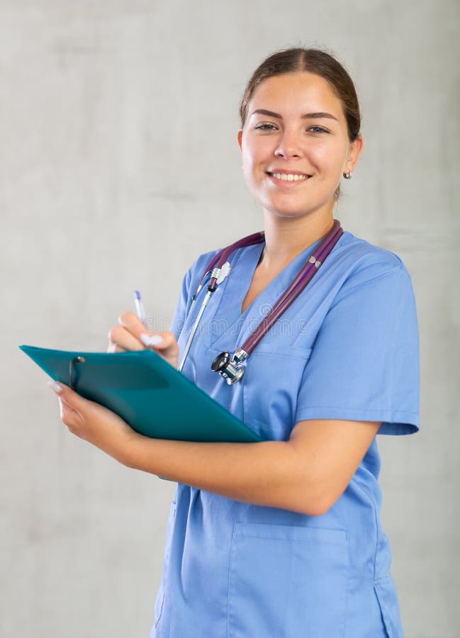 Young Happy Female Nurse Writing in File with Papers Stock Image ...