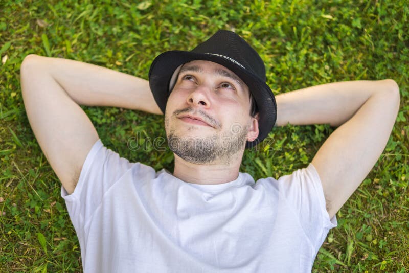 Young Happy Man is Lying and Relaxing in Grass in Park and Thinking or ...