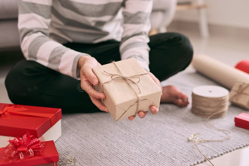 Young Happy Man Packing Valentine Gift while Sitting on Floor Stock ...