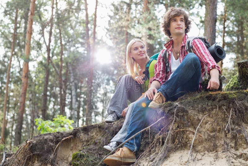 Young Hiking Couple Sitting on Edge of Cliff in Forest Stock Photo ...