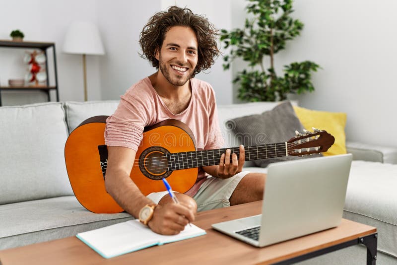 Young Hispanic Composer Man Composing Song Using Guitar and Laptop at ...