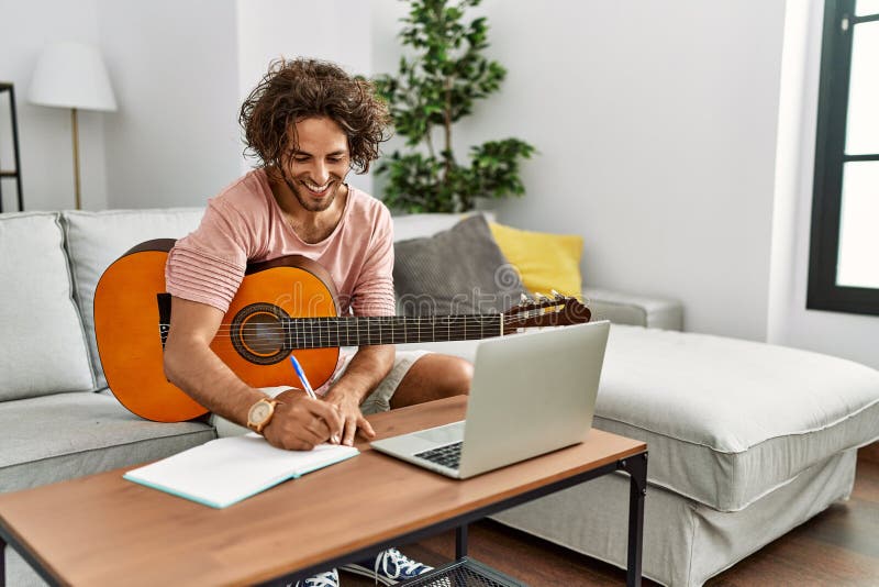 Young Hispanic Composer Man Composing Song Using Guitar and Laptop at ...