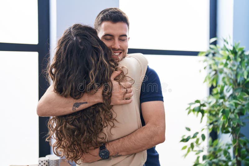 Young Hispanic Couple Business Workers Hugging Each Other Standing at ...