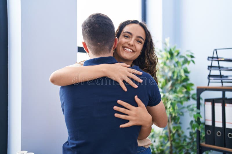 Young Hispanic Couple Business Workers Hugging Each Other Standing at ...