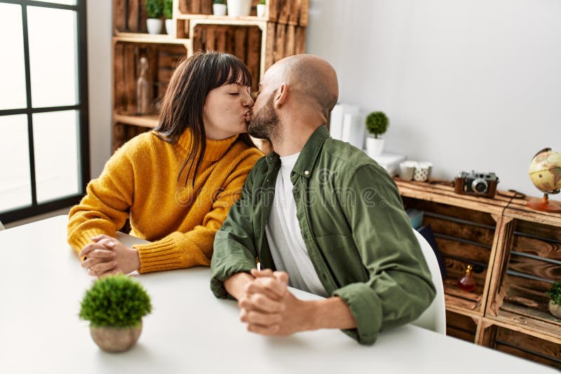 Young Hispanic Couple Sitting on the Table Kissing at Home Stock Image ...