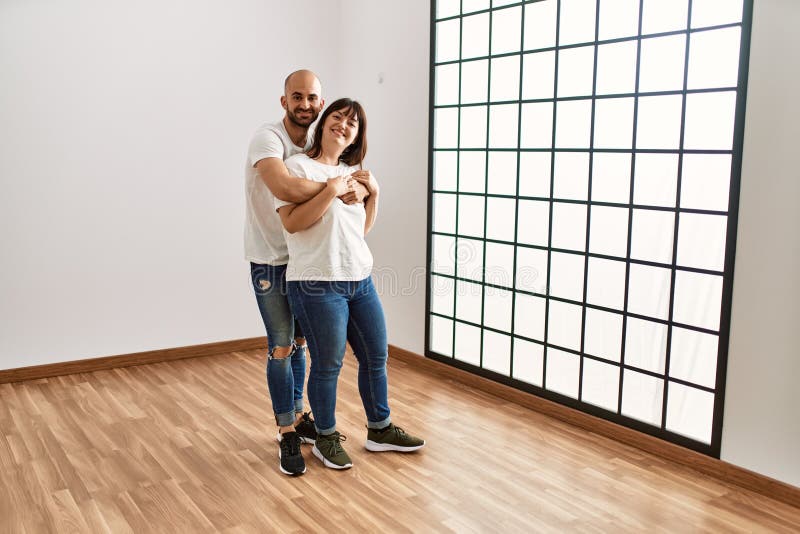 Young Hispanic Couple Smiling Happy and Hugging at Empty New Home Stock ...
