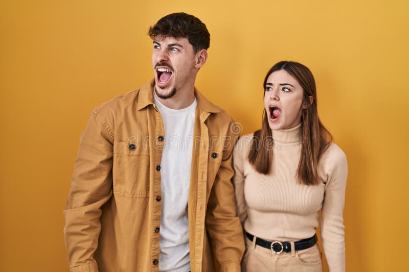 Young Hispanic Couple Standing Over Yellow Background Angry and Mad ... Young Hispanic Couple Standing Over Yellow Background Angry and Mad ...