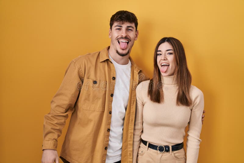 Young Hispanic Couple Standing Over Yellow Background Sticking Tongue ... Young Hispanic Couple Standing Over Yellow Background Sticking Tongue ...