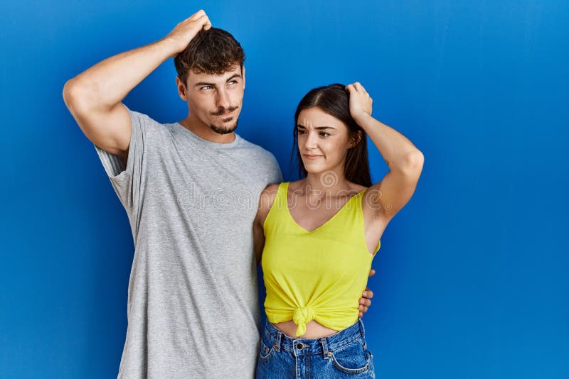 Young Hispanic Couple Standing Together Over Blue Background Confuse ...