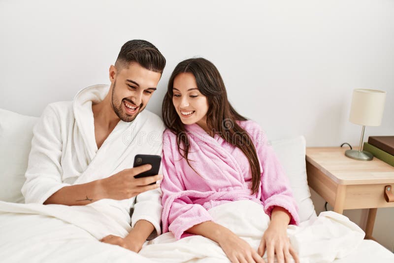 Young Hispanic Couple Using Smartphone Lying on Bed at Home Stock Photo ...