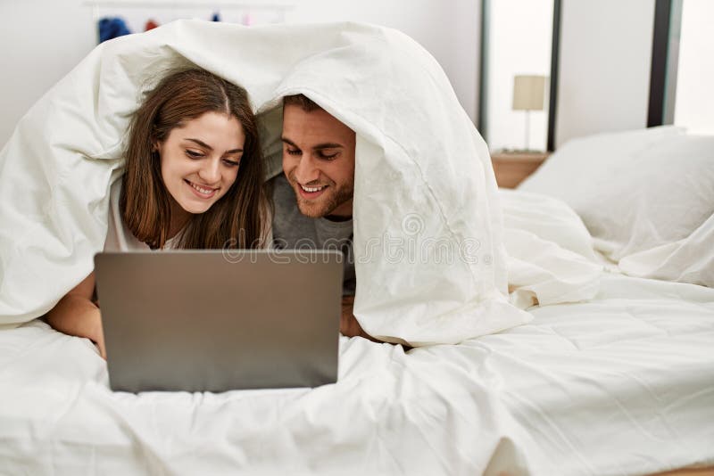 Young Hispanic Couple Watching Movie Using Laptop Lying in Bed Stock ...