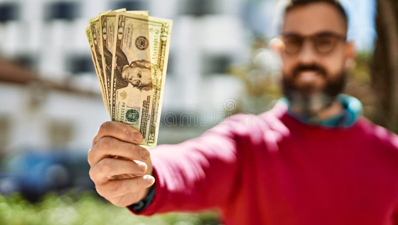 Young Hispanic Executive Man Smiling Happy Holding Dollars at the City ...