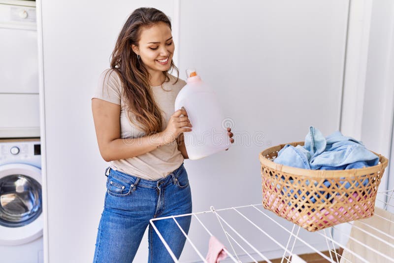 Young Hispanic Girl Doing Laundry Holding Detergent Bottle at Home ...