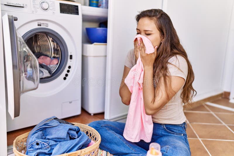 Young Hispanic Girl Doing Laundry Smelling Clean Clothes at Home Stock ...