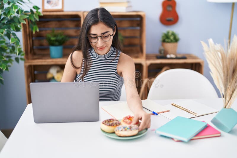 Young Hispanic Girl Eating Doughnut Studying at Home Stock Image ...