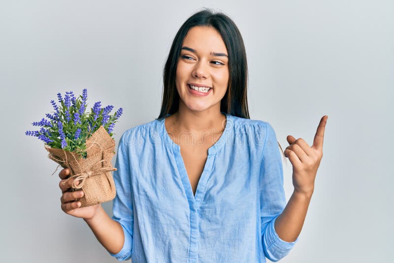 Young Hispanic Girl Holding Lavender Plant Smiling Happy Pointing With