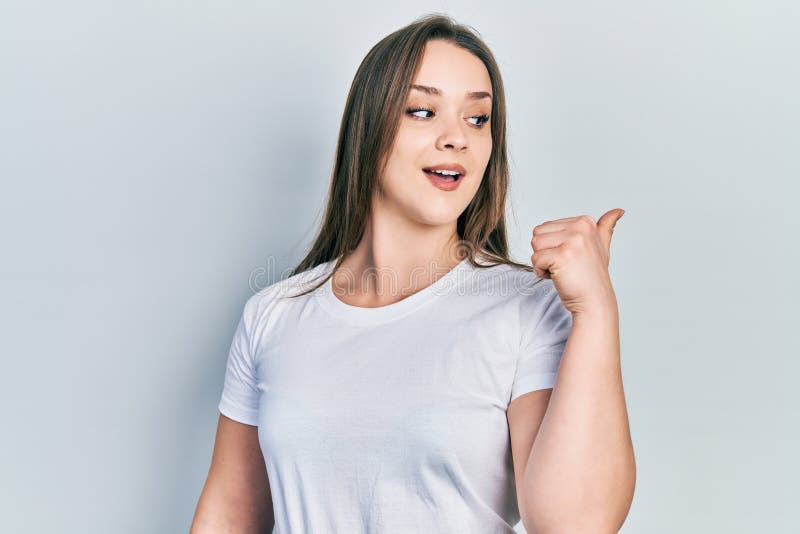 Young Hispanic Girl Wearing Casual White T Shirt Pointing Thumb Up To