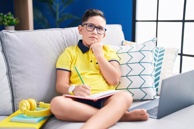 Young Hispanic Kid Doing Homework Sitting on the Sofa with Hand on Chin ...