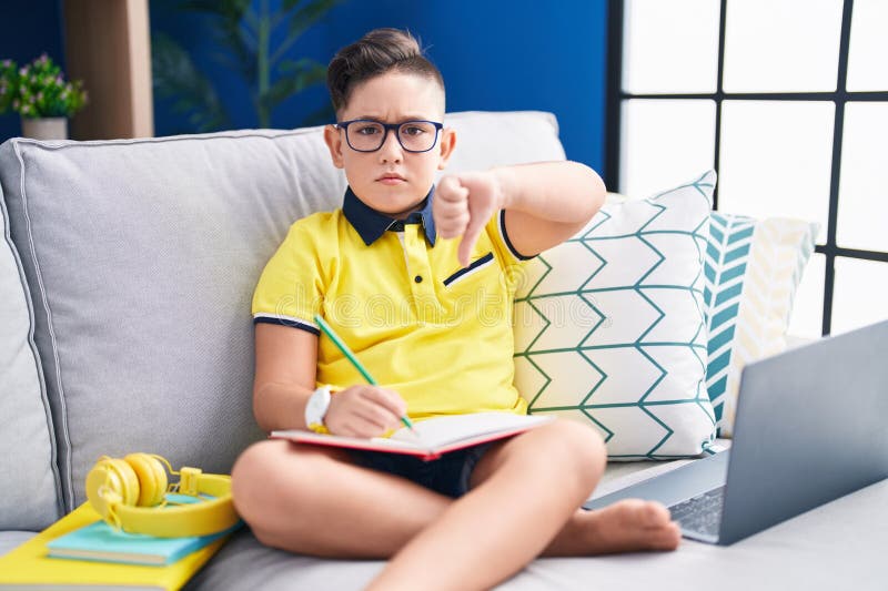 Young Hispanic Kid Doing Homework Sitting on the Sofa Looking Unhappy ...