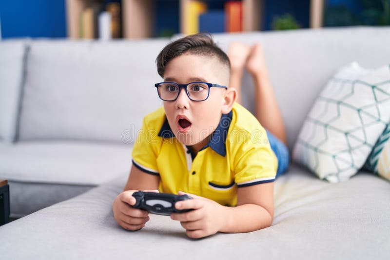 Young Hispanic Kid Playing Video Game Holding Controller on the Sofa ...
