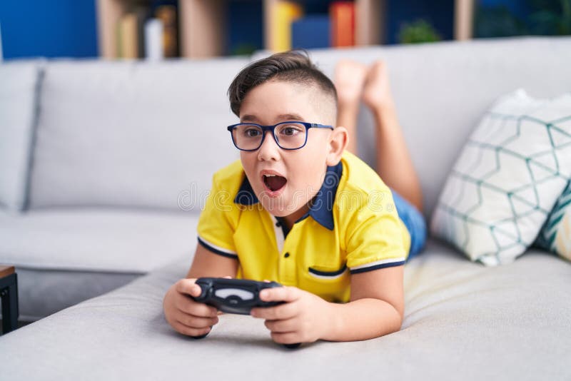 Young Hispanic Kid Playing Video Game Holding Controller on the Sofa ...