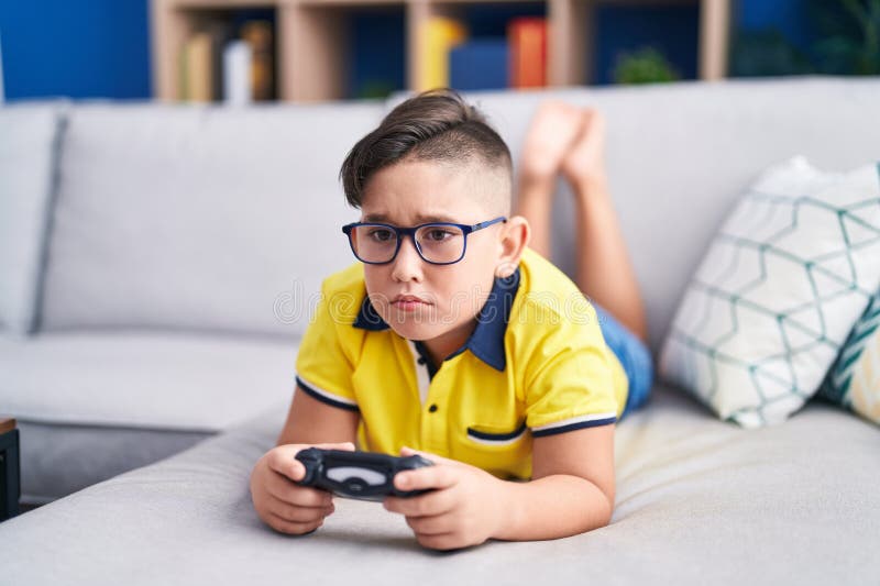 Young Hispanic Kid Playing Video Game Holding Controller on the Sofa ...