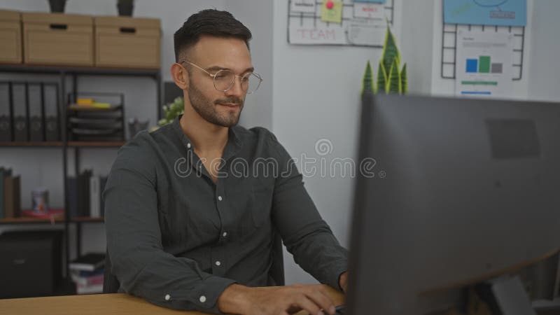 A Young Hispanic Man with a Beard and Glasses, Working in an Office ...
