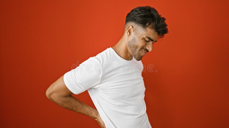 A Young Hispanic Man with a Beard Winces in Pain, Touching His Lower ...