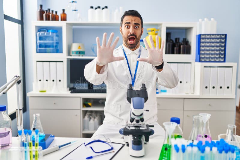Young Hispanic Man with Beard Working at Scientist Laboratory Afraid ...