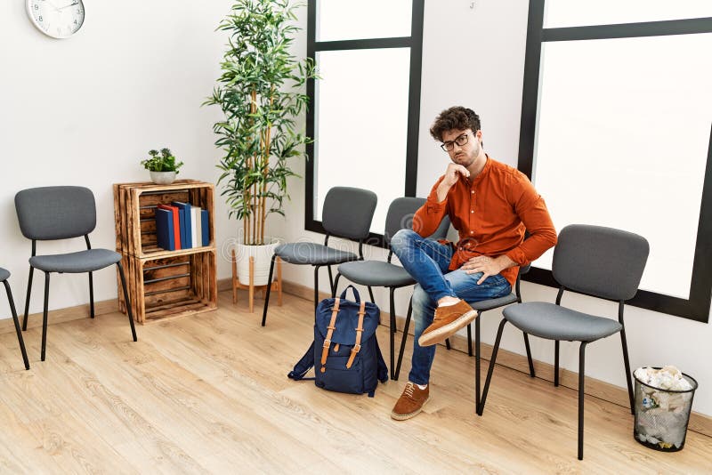 Young Hispanic Man Boring Sitting on Chair at Waiting Room Stock Photo ...
