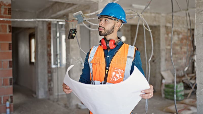 Young Hispanic Man Builder Standing with Blueprints at Construction ...