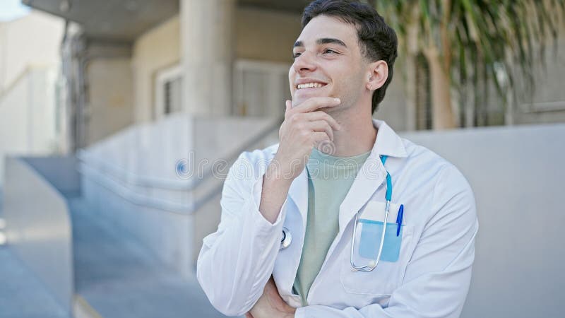 Young Hispanic Man Doctor Smiling Confident Thinking at Hospital Stock ...