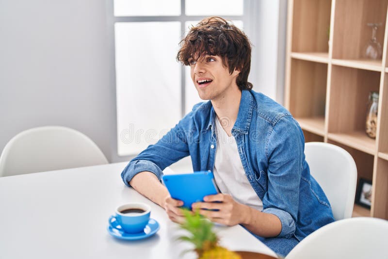 Young Hispanic Man Driking Coffee Using Touchpad at Home Stock Photo ...