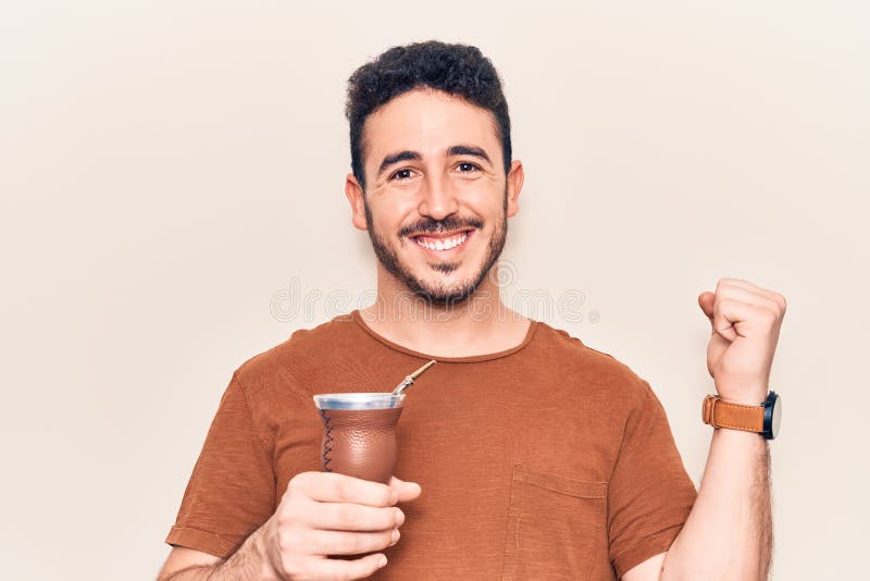 Young Hispanic Man Drinking Mate Infusion Screaming Proud Celebrating