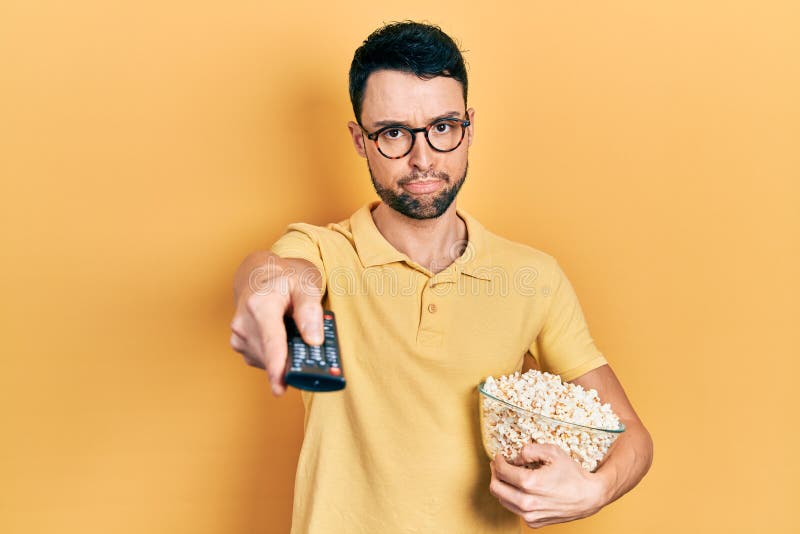 Young Hispanic Man Eating Popcorn Using Tv Control Depressed and Worry ...