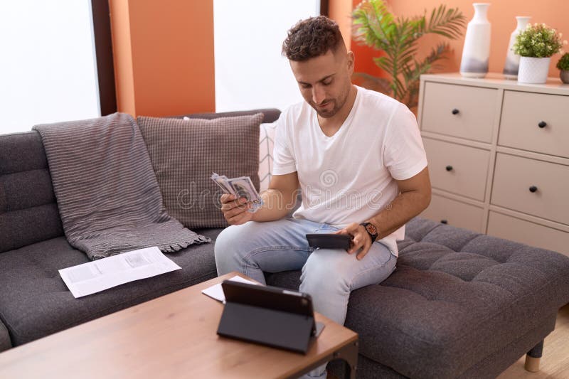 Young Hispanic Man Holding Dollars Using Calculator Accounting at Home ...