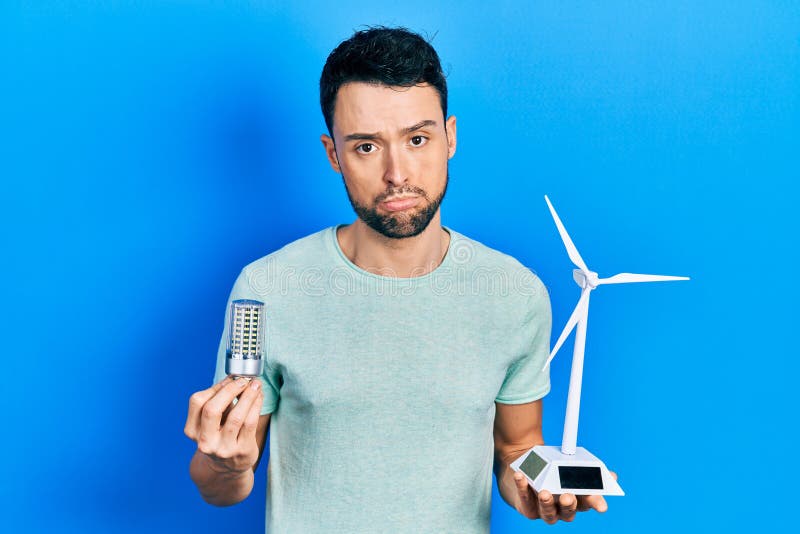 Young Hispanic Man Holding Windmill and Led Lightbulb Depressed and ...