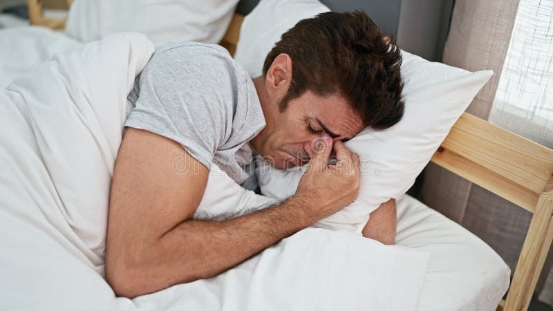 Young Hispanic Man Lying on Bed with Sad Expression Crying at Bedroom ...
