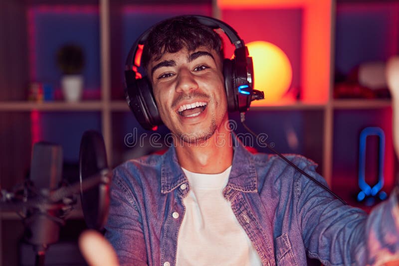 Young Hispanic Man Playing Video Games Looking at the Camera Smiling ...