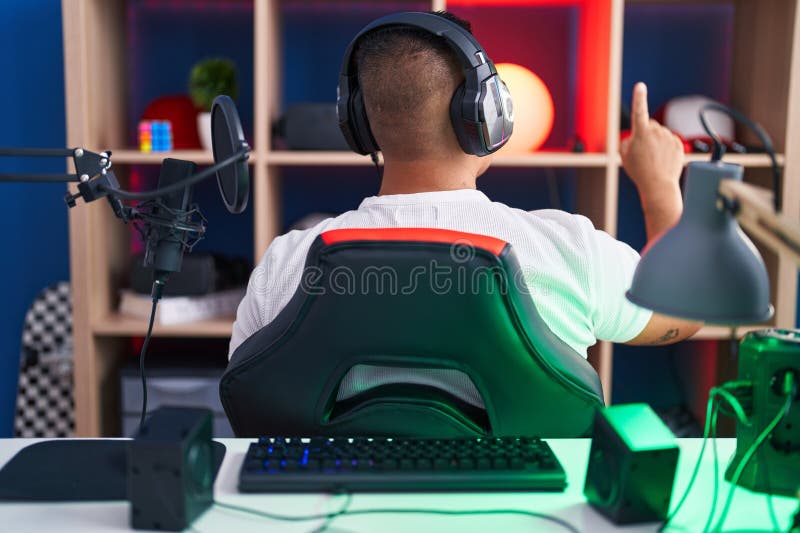 Young Hispanic Man Playing Video Games Posing Backwards Pointing Ahead ...